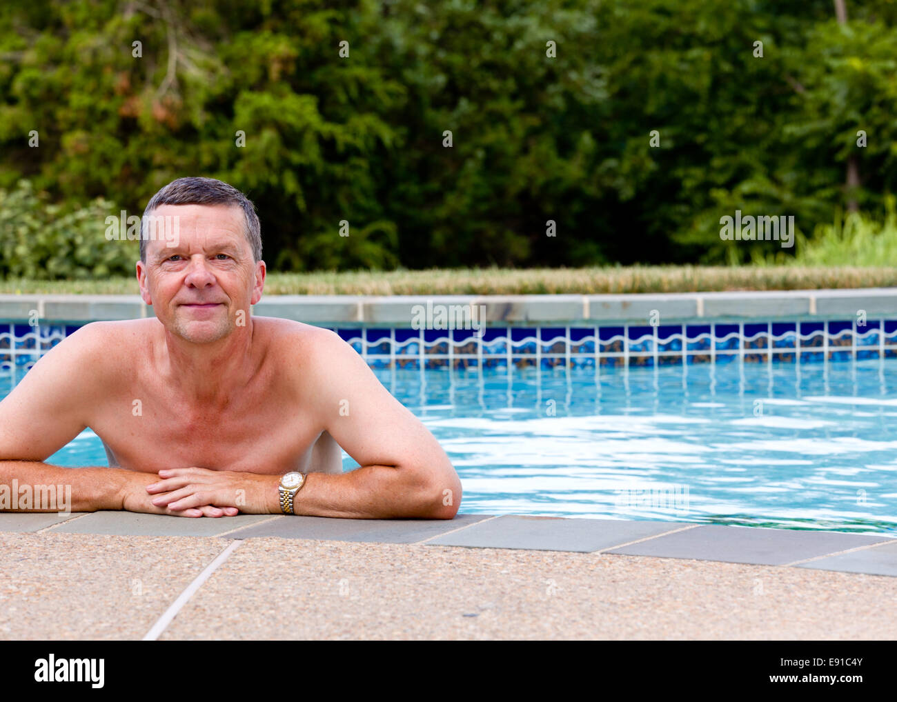 Senior man by edge of swimming pool Stock Photo - Alamy