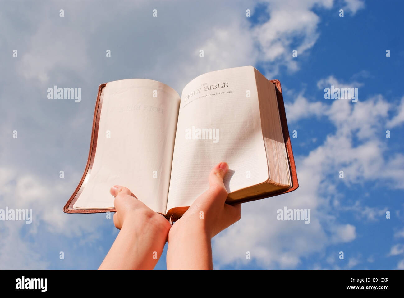 Hands hold the open Bible against blue sky Stock Photo - Alamy