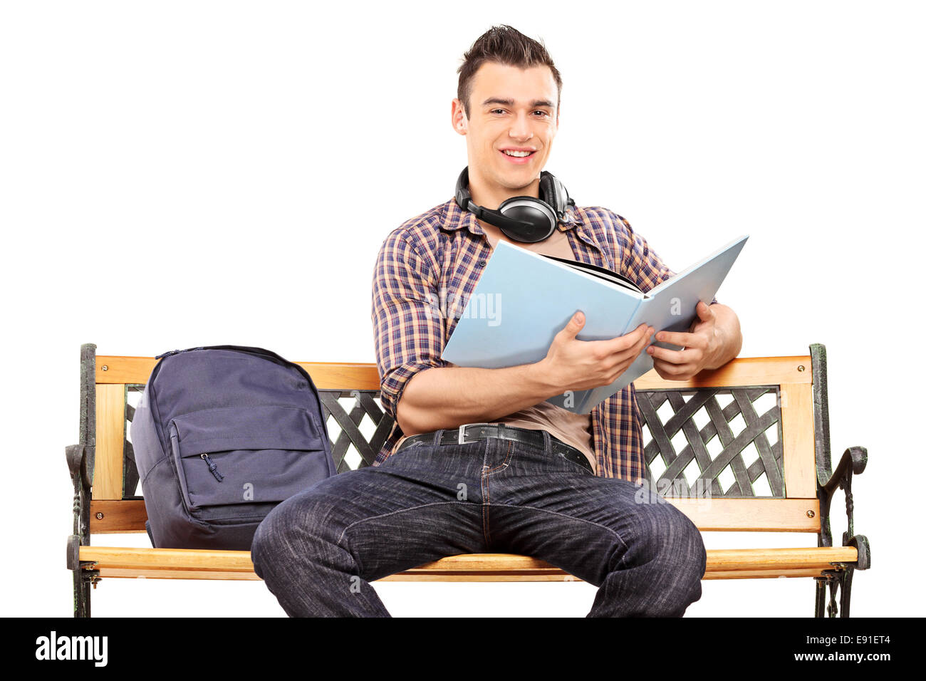 Student with headphones reading a book seated on a bench isolated on ...