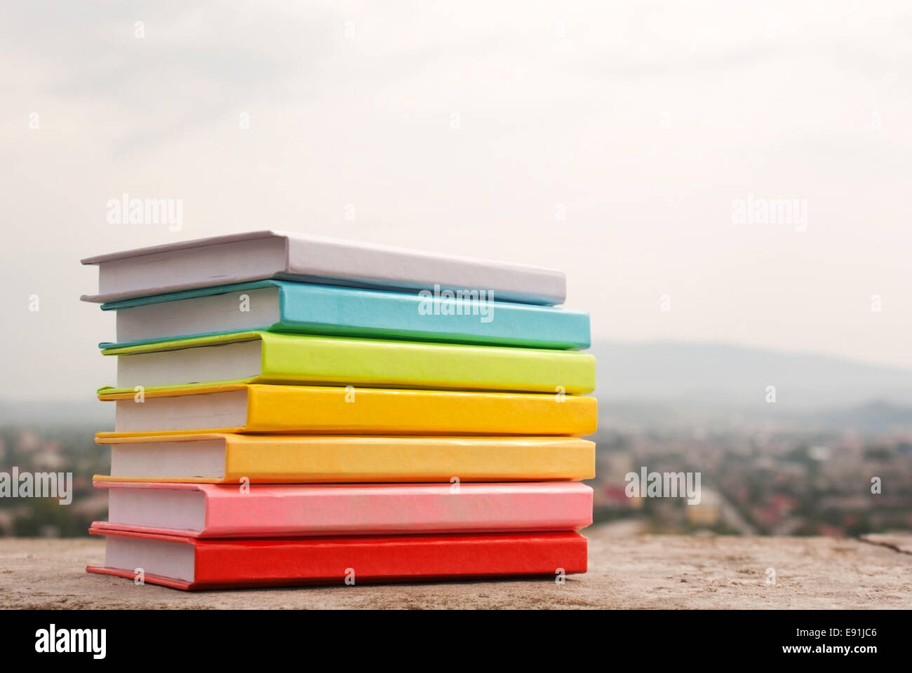 Stack of colorful books laying outdoors Stock Photo - Alamy