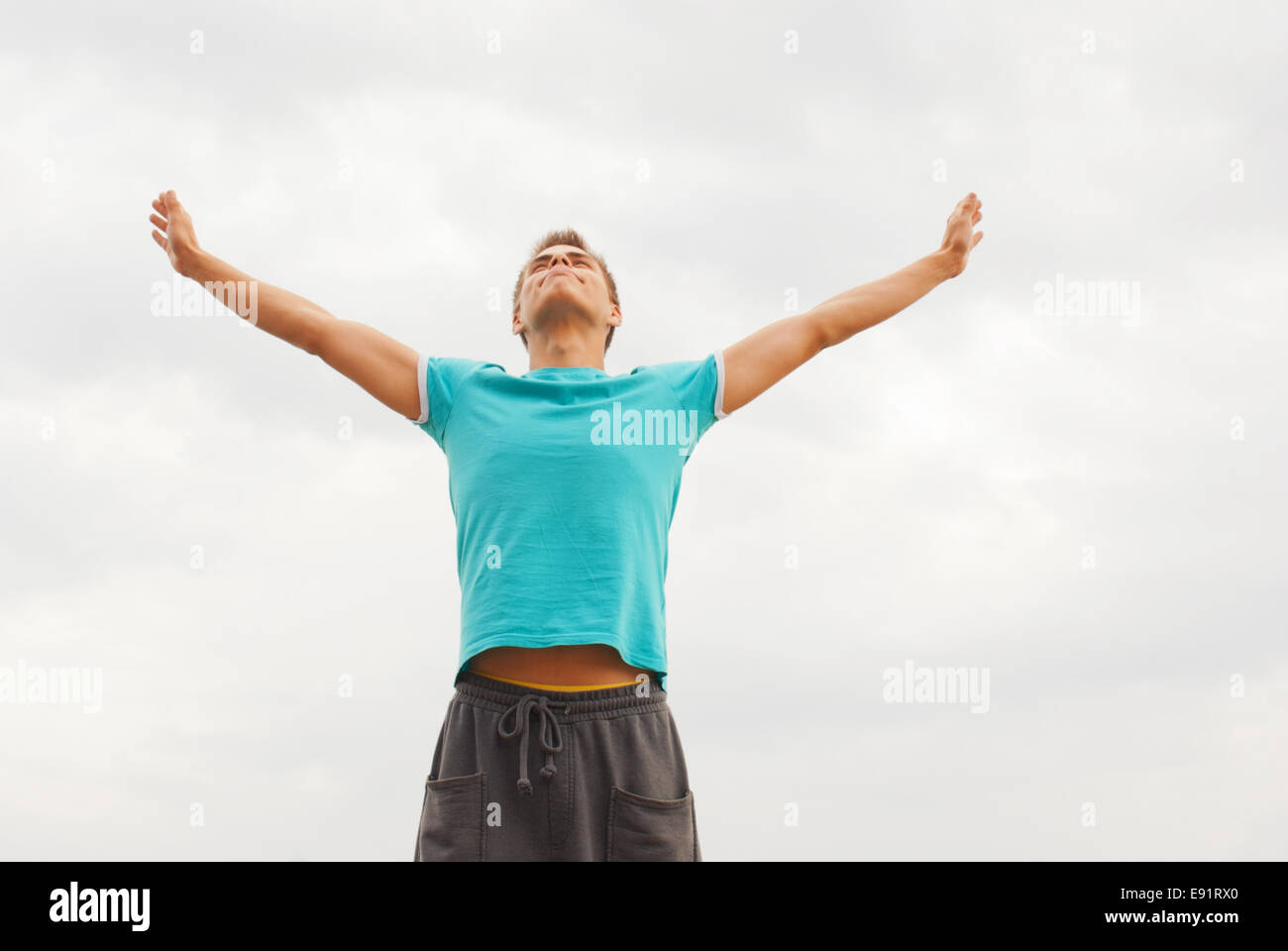 Young man staying with raised hands Stock Photo - Alamy