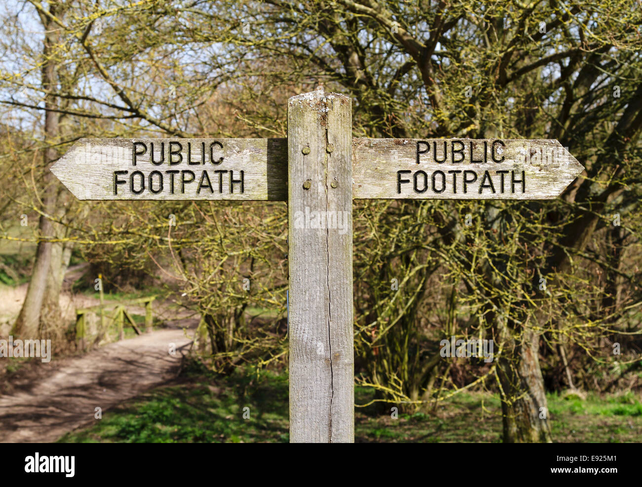 Public footpath sign pointing left and right against a forest ...
