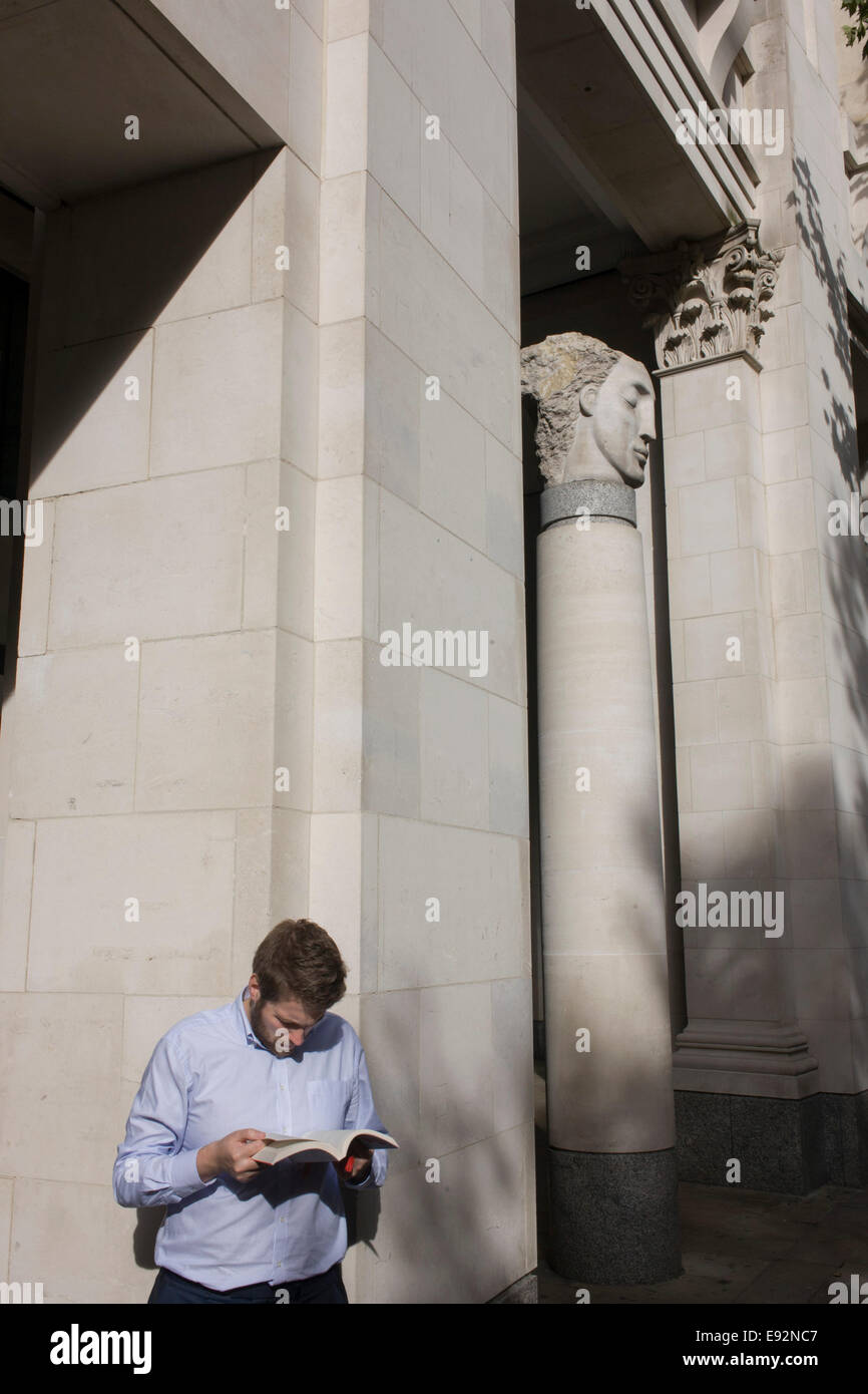 Educated man reading book with City of London sculpture Stock Photo - Alamy