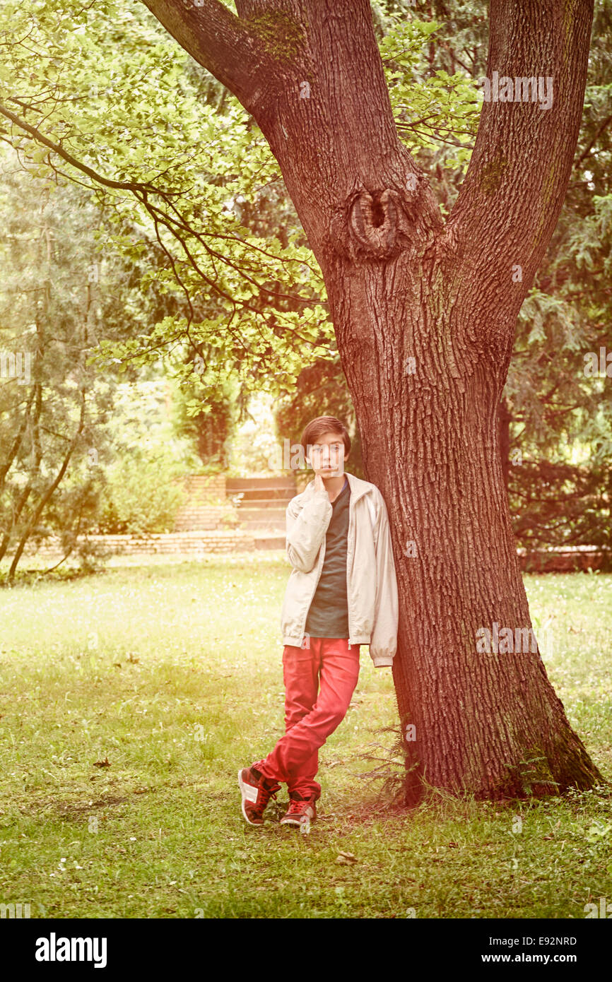 Boy leaning against tree hi-res stock photography and images - Alamy