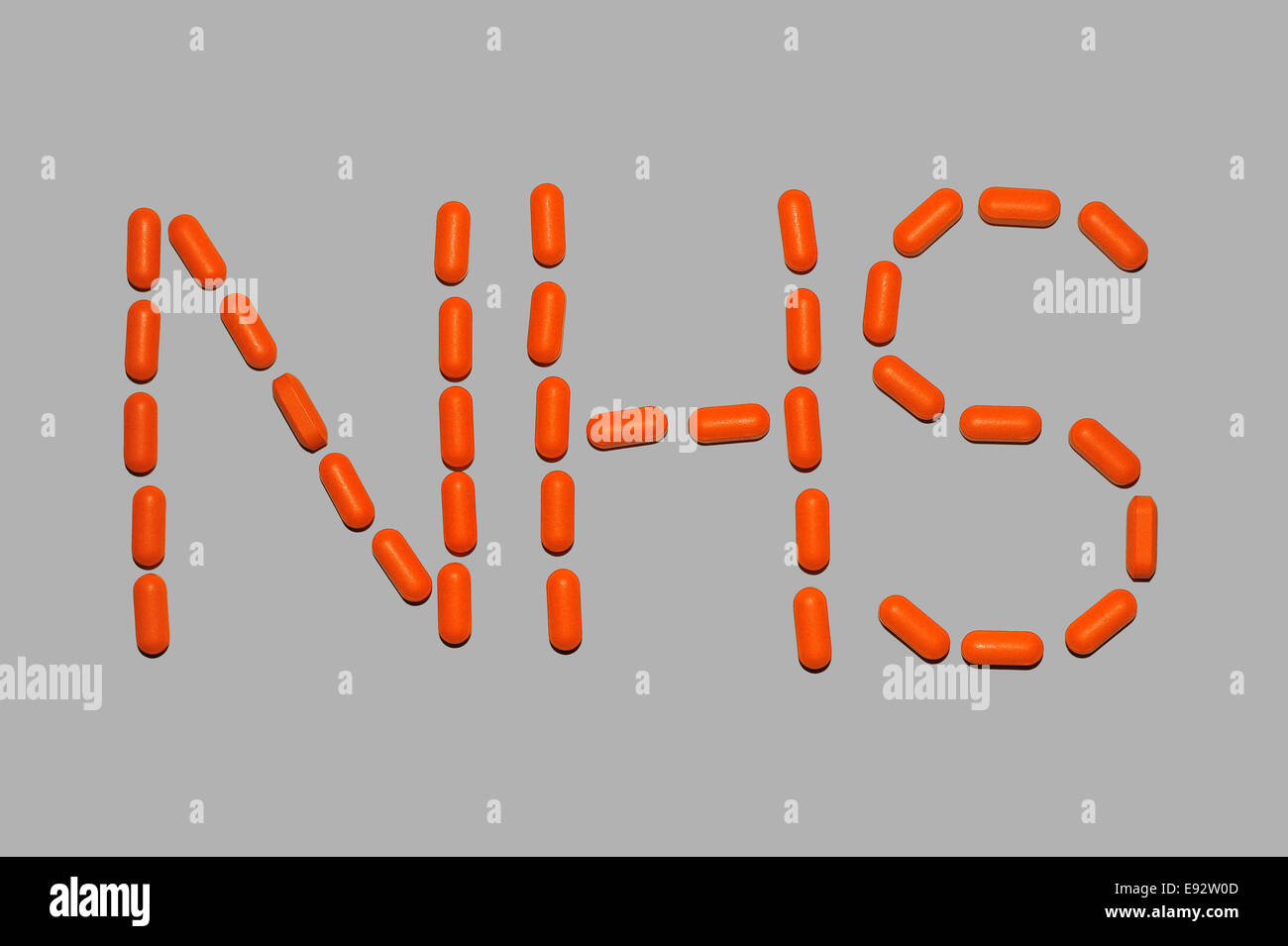 An image of the word NHS made from orange medical pills against a gray ...