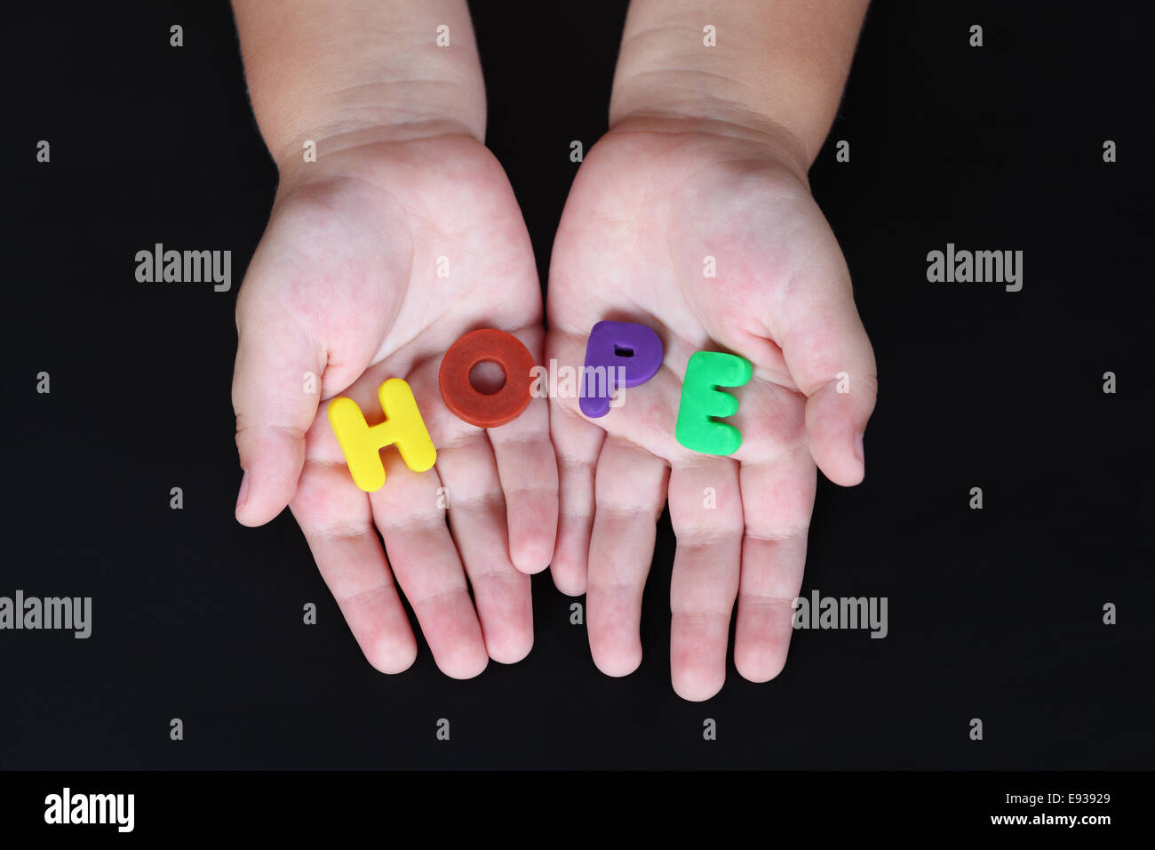 Word "Hope" in child's hands on black background. Letters made of child ...