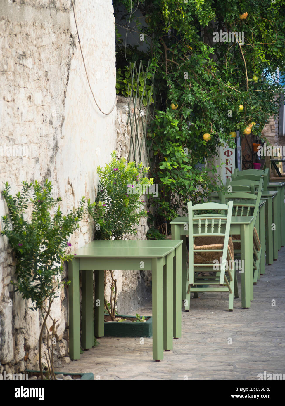 Typical Greek pavement café, colourful green wooden tables and chairs ...