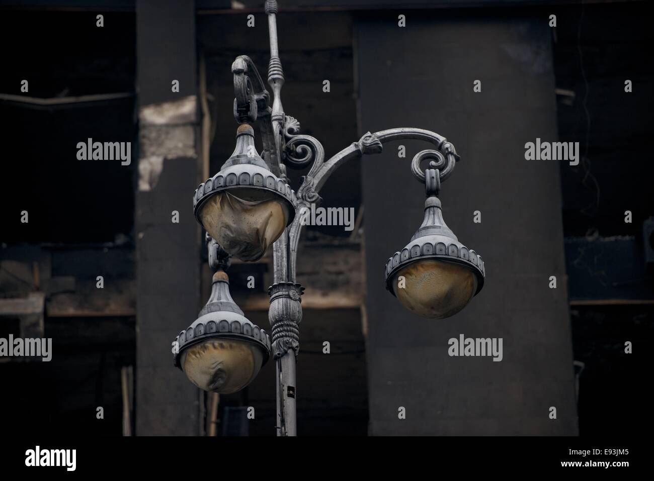 Charred and melted street lamps in front of a burned out building ...