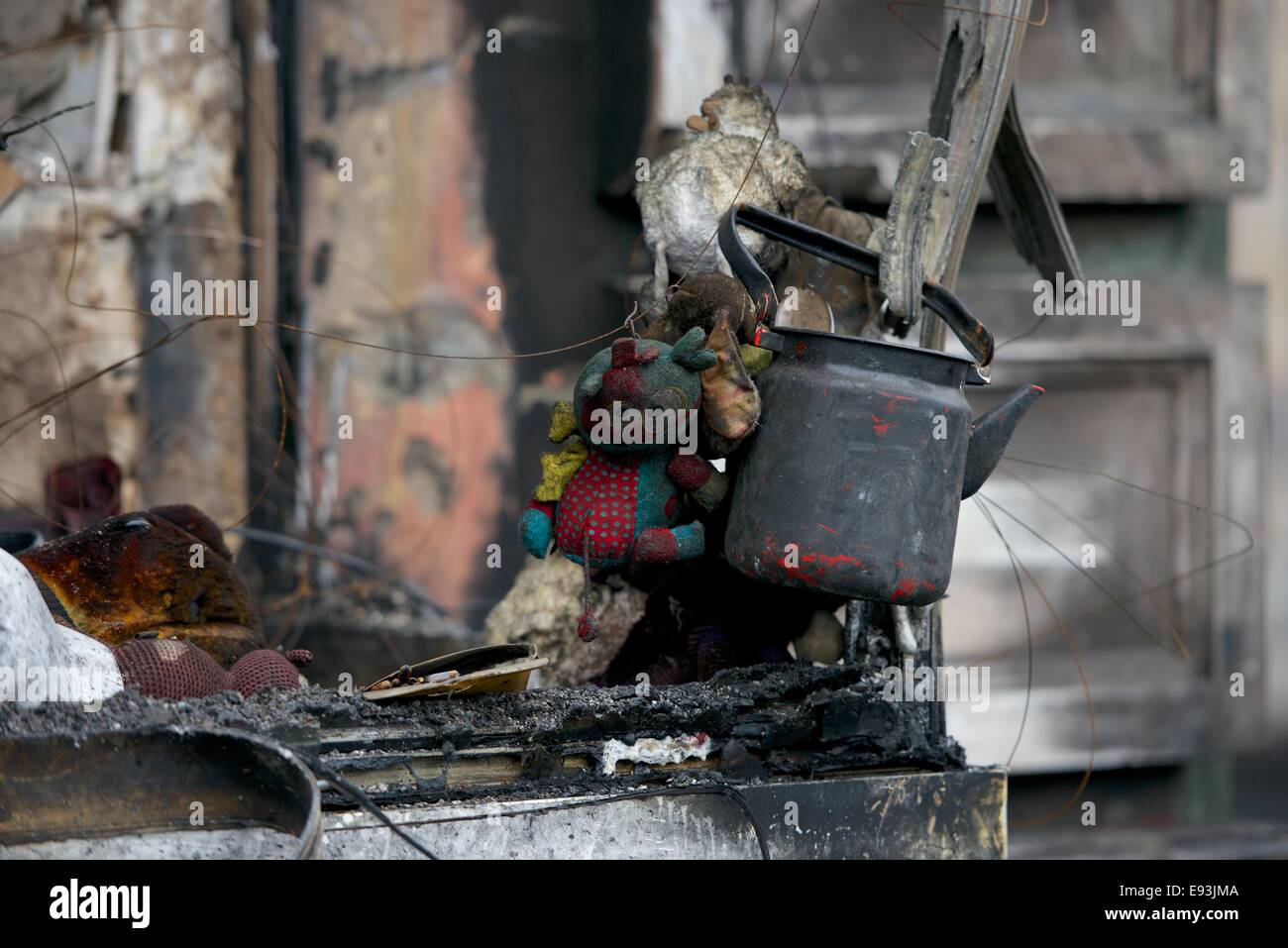 A soot covered teapot and childs knitted toy hang froma burned out shop ...