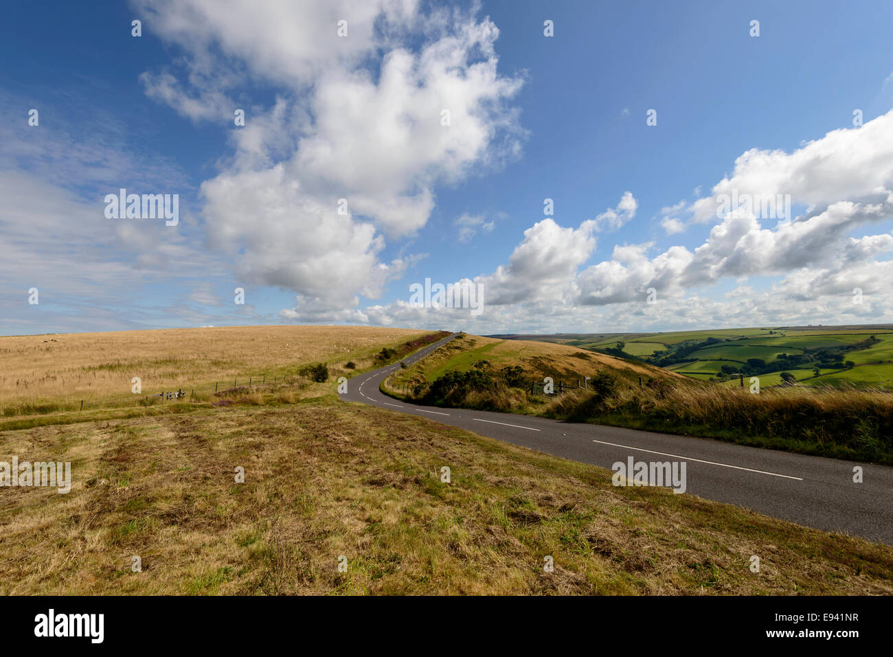 landscape of moor with empty road bending under a bright cloudy sky ...