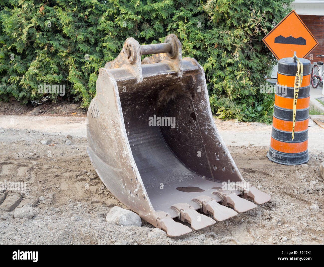 Bucket for a loader sits on the side of a street next to a bump sign ...