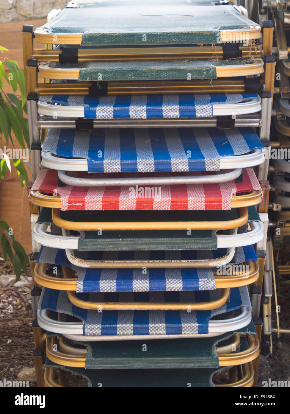 Stack of old faded sunbeds set aside after the end of the summer ...