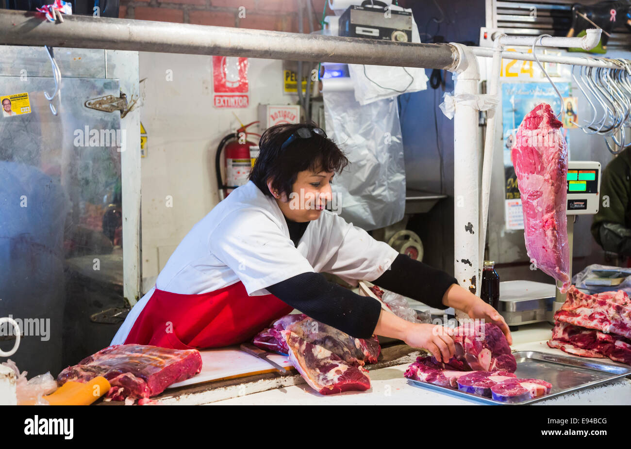 Local Peruvian woman stallholder serving meat at a butcher's stall ...