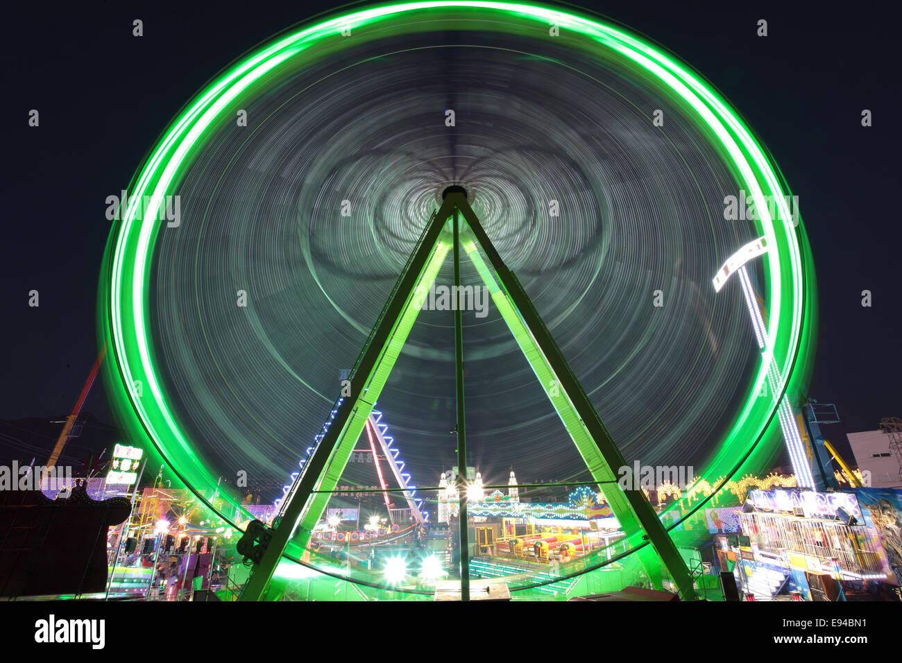 Long exposure image of ferris wheel and other rides at funfair at night ...