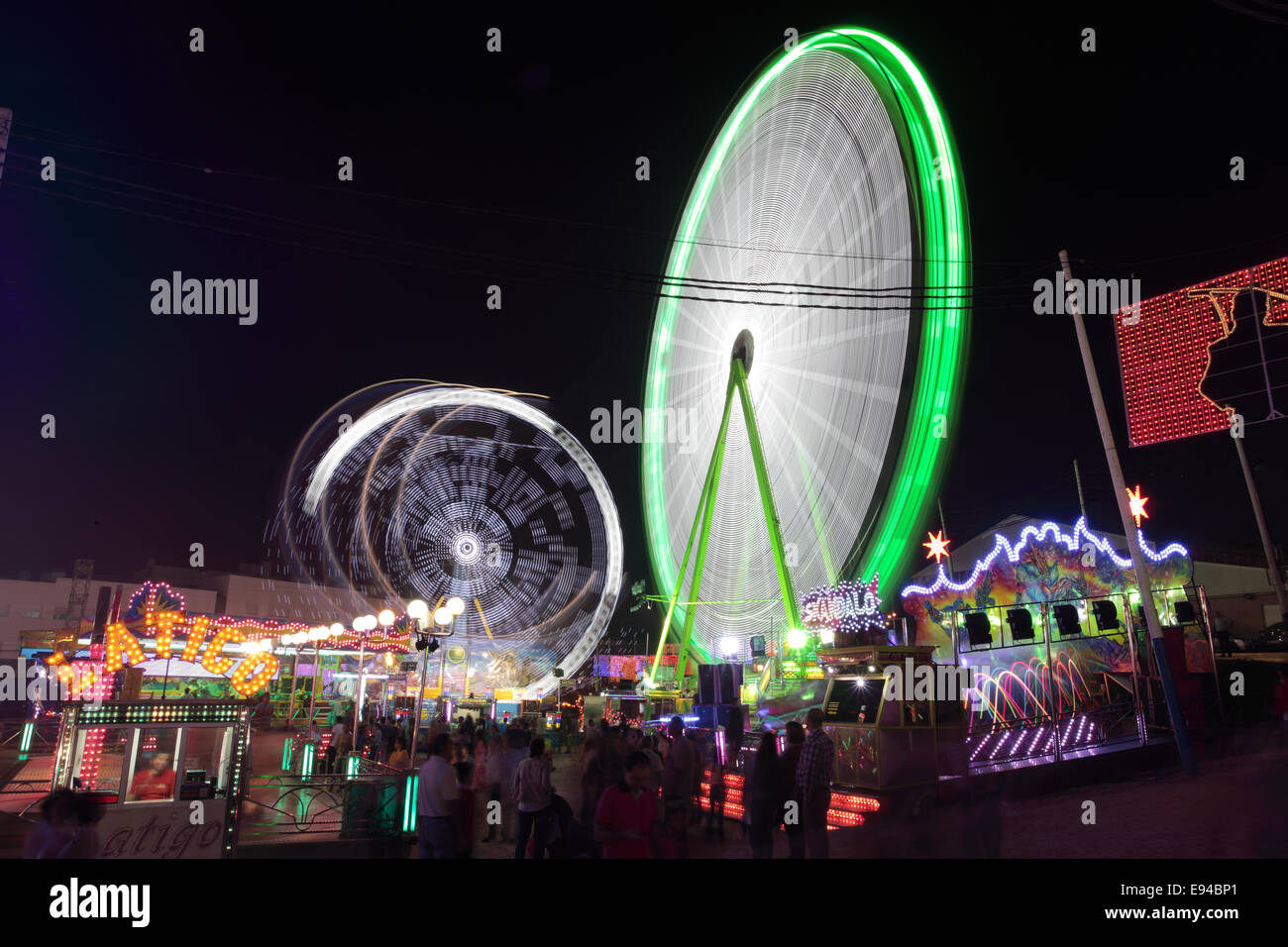 Long exposure image of ferris wheel and other rides at funfair at night ...