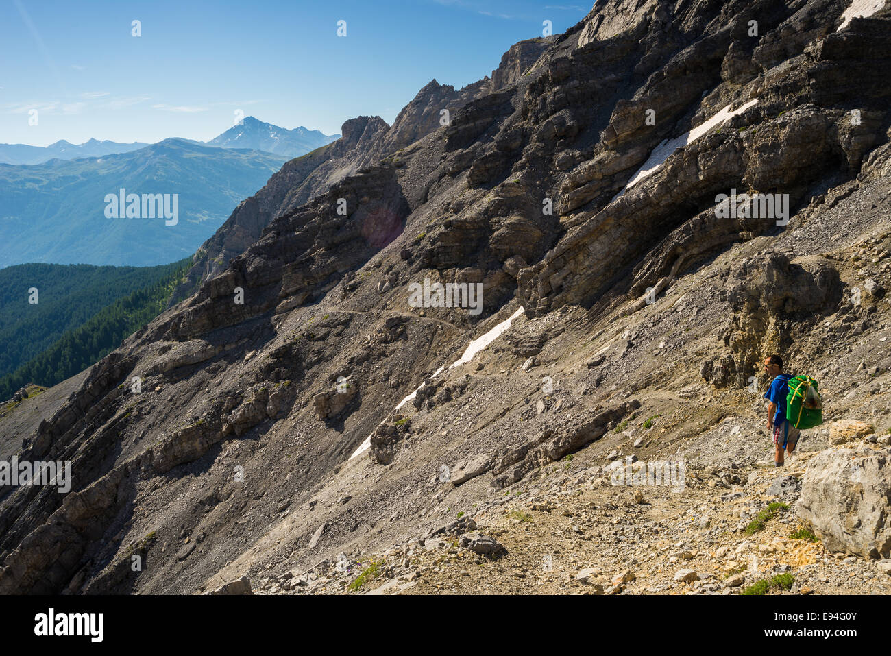 Hiker walking on dangerous footpath crossing a steep rocky slope with ...