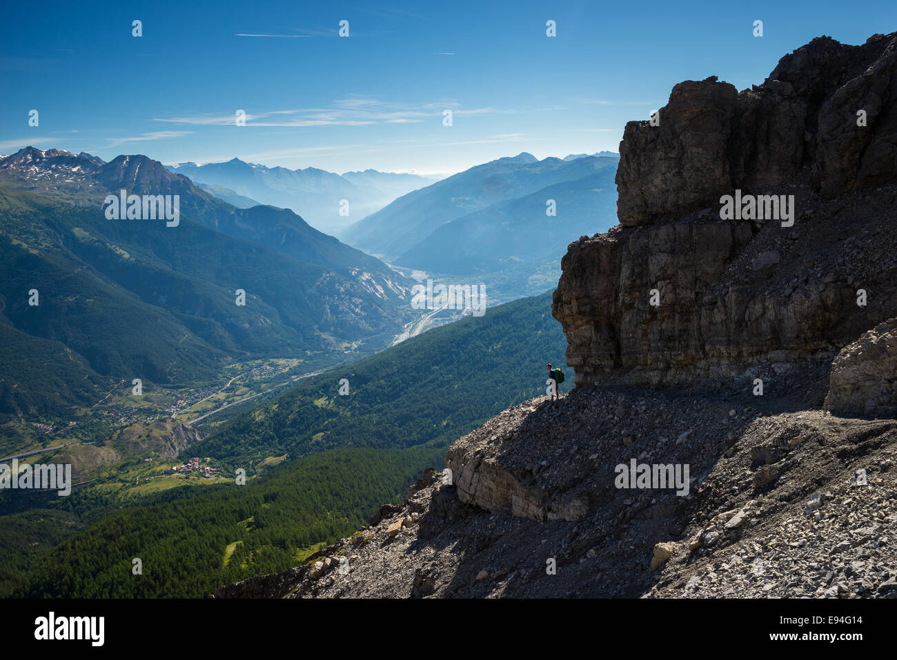 Hiker walking on dangerous footpath crossing a steep rocky slope with ...