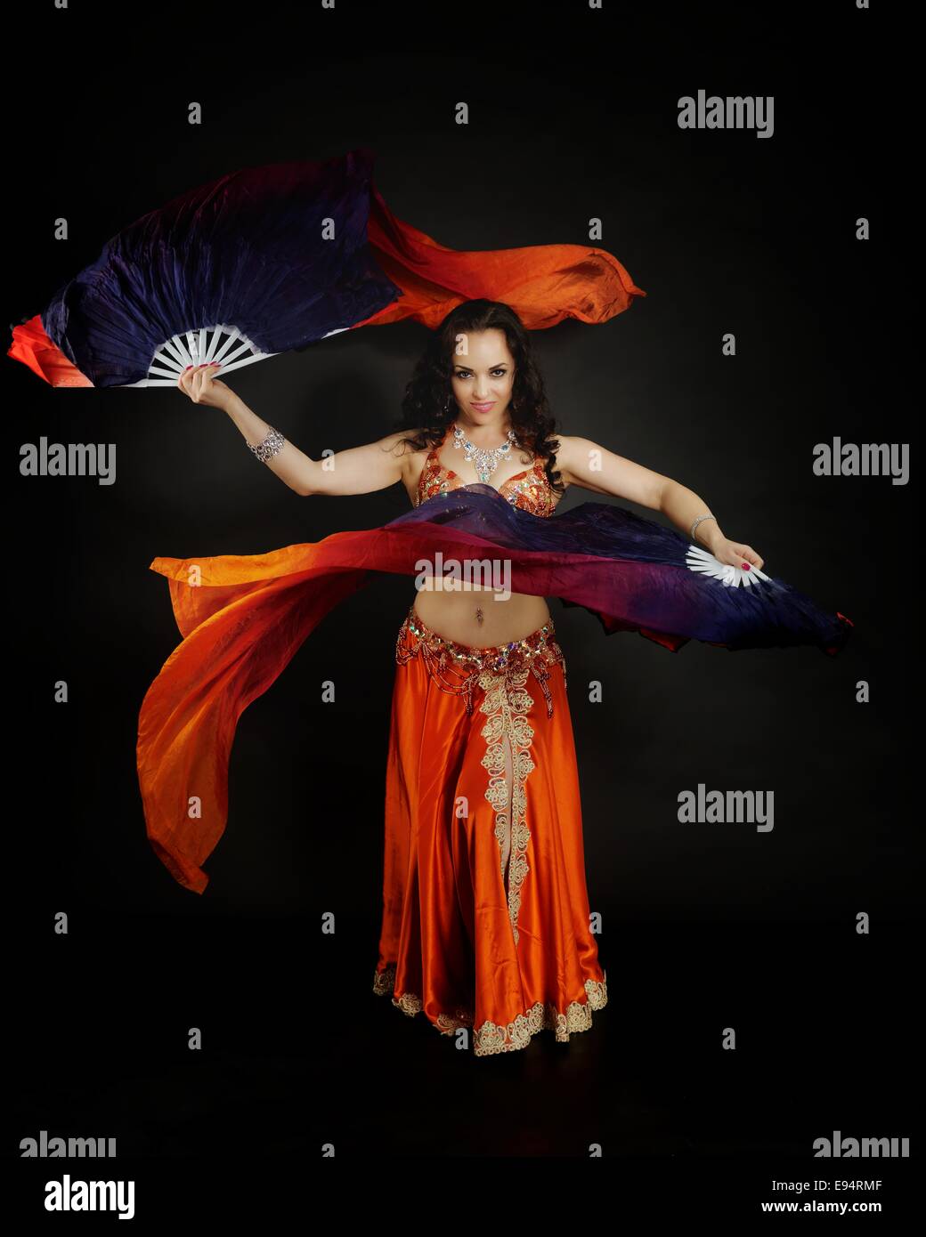 Young beautiful belly dancer wearing a colorful costume, holding two ...