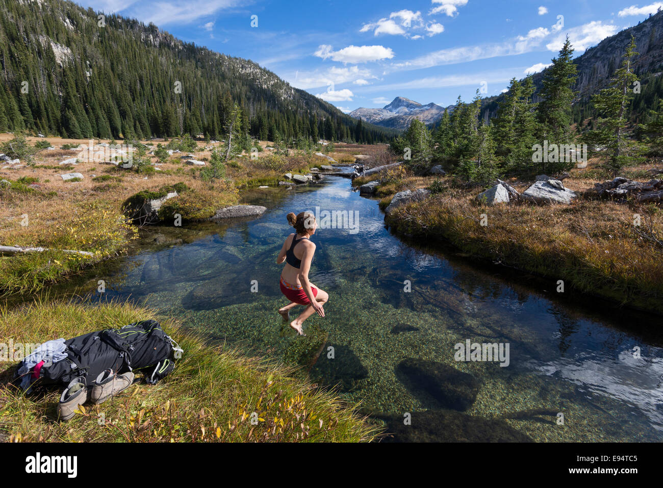 Woman jumping into a stream on a backpack trip in Oregon's Wallowa ...