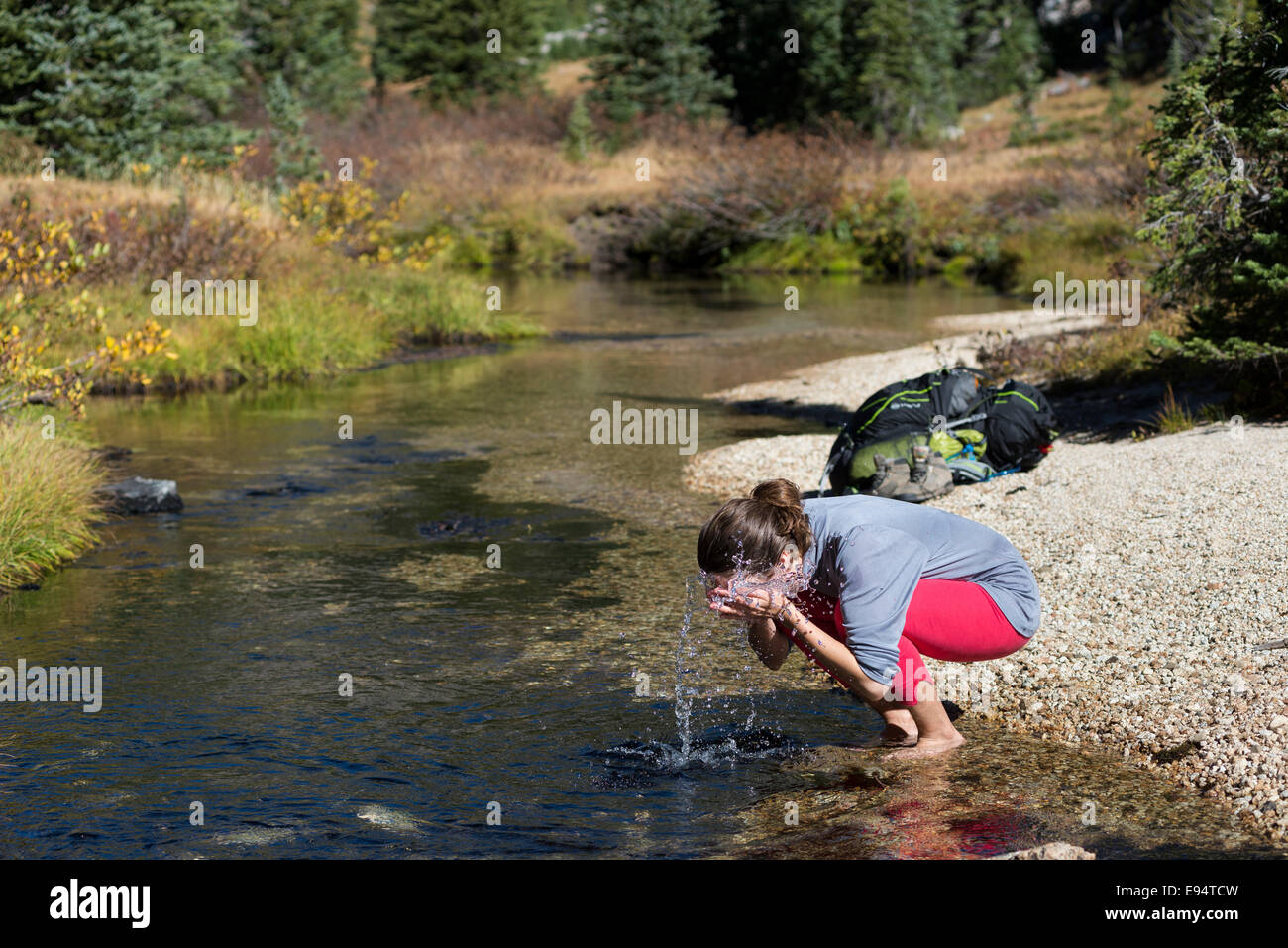 Woman splashing water on her face from a stream in Oregon's Wallowa ...