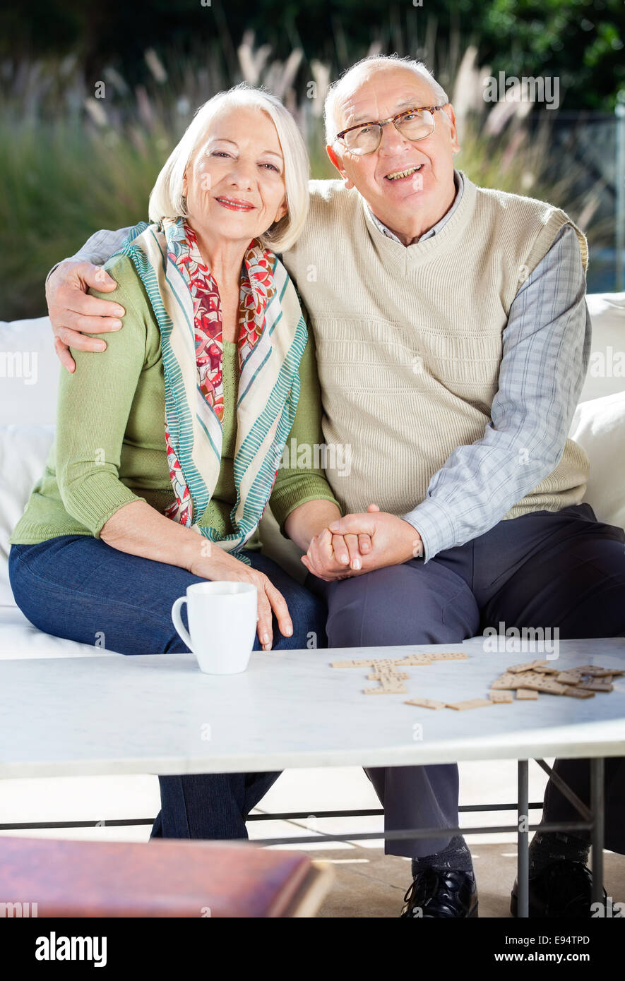 Senior Man Sitting With Arm Around Woman On Couch Stock Photo - Alamy