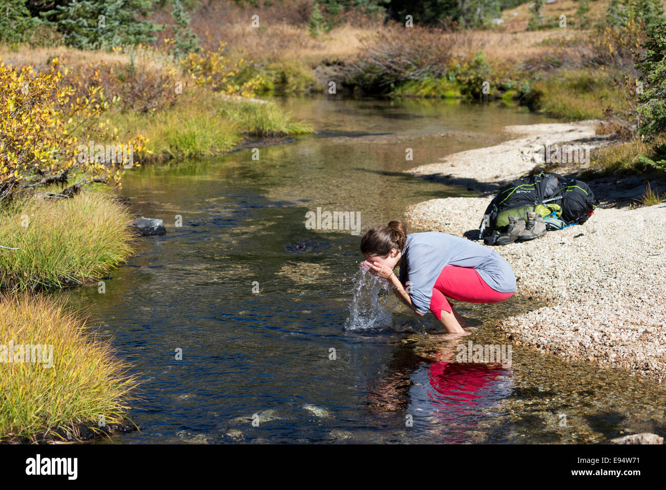 Woman splashing water on her face from a stream in Oregon's Wallowa ...