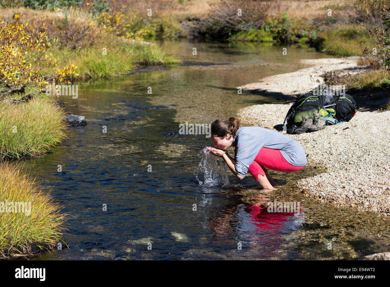Woman splashing water on her face from a stream in Oregon's Wallowa ...