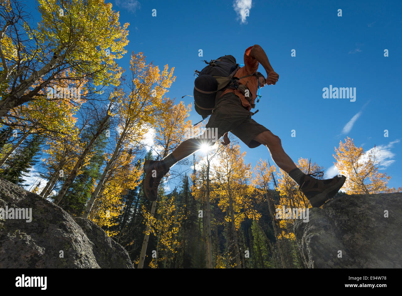 Backpacker leaping from boulder to boulder on a talus slope in Oregon's ...