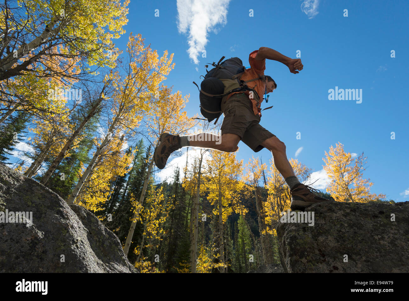 Backpacker leaping from boulder to boulder on a talus slope in Oregon's ...