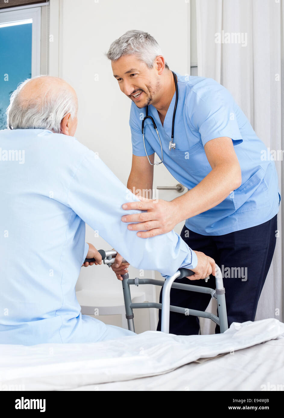 Caretaker Assisting Senior Man To Use Walking Frame Stock Photo - Alamy