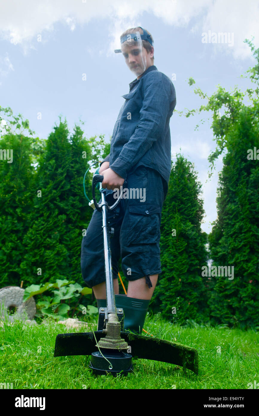 Guy with lawn mower in front of back yard Stock Photo - Alamy