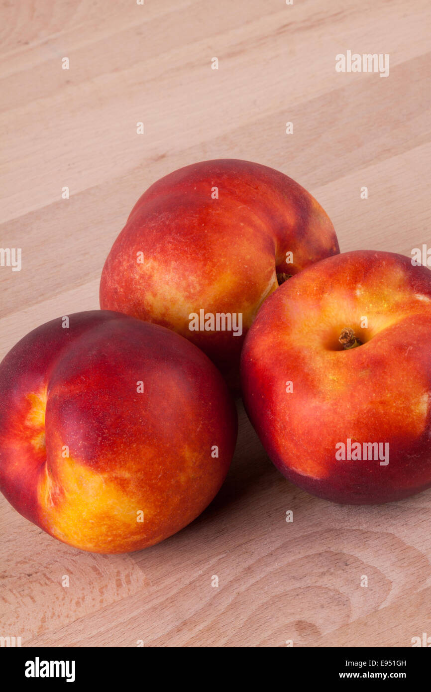 Three tasty fresh ripe juicy nectarines on white painted wooden boards ...