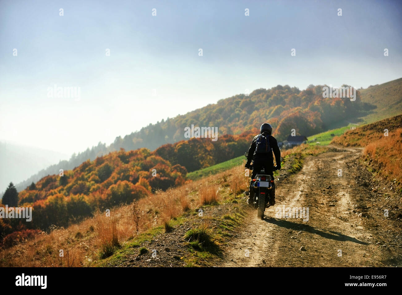 Autumn scene with a motorcycle on a mountain dirt road at golden hour ...