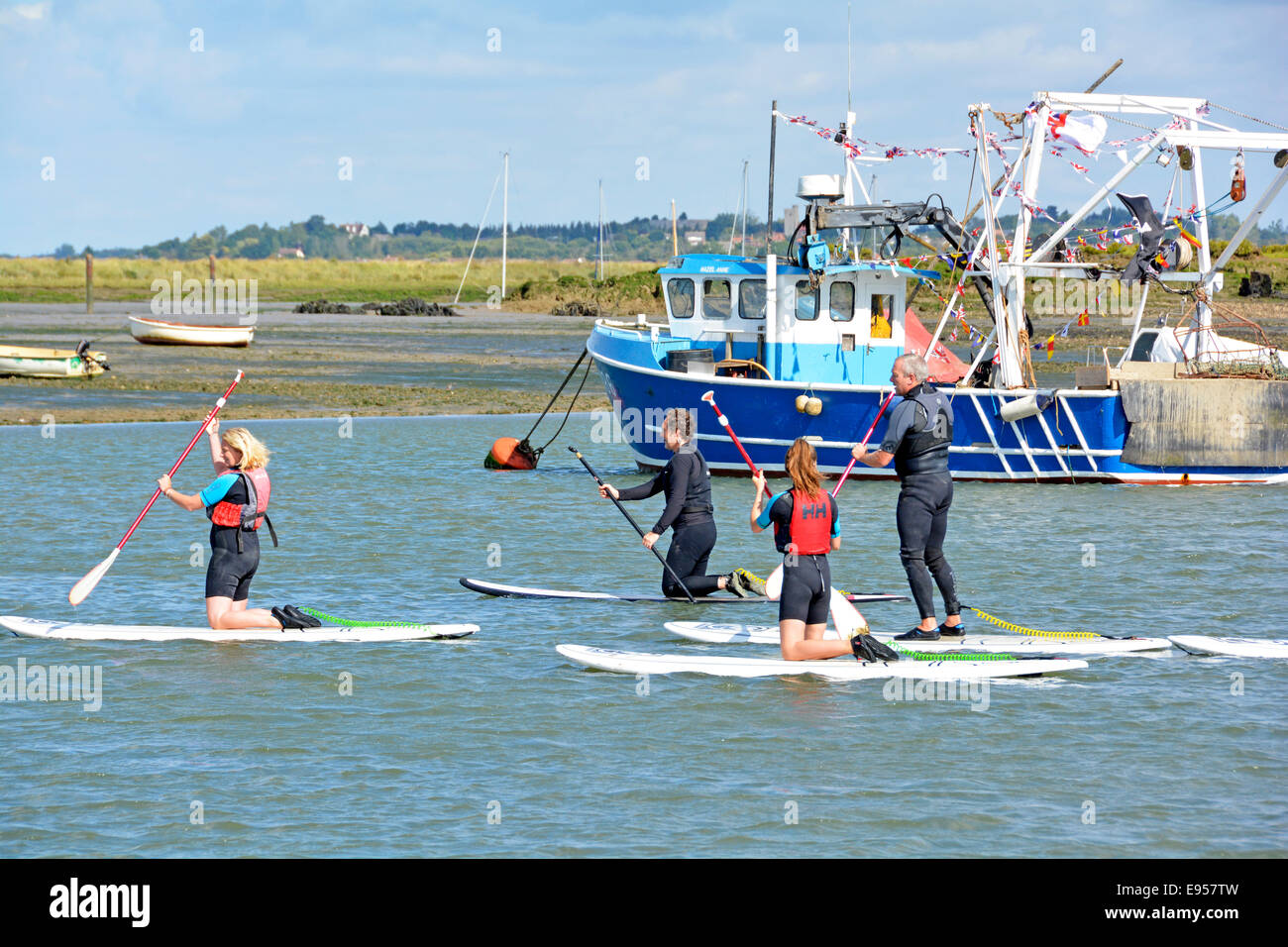 Group of people paddle boarding by kneeling on the board with one man ...