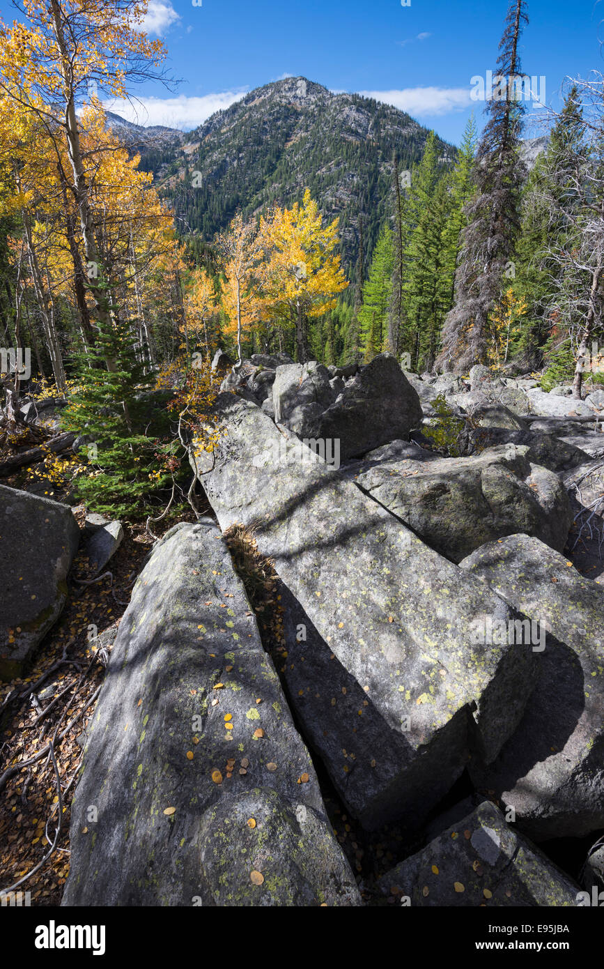 Backpacker balancing as he walks along the narrow top edge of a boulder ...