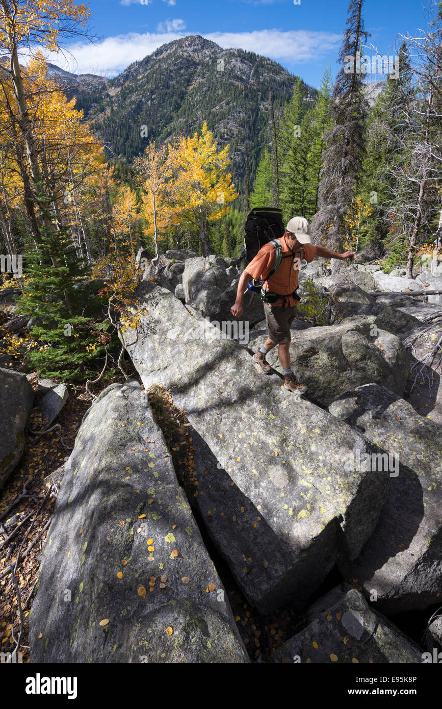 Backpacker balancing as he walks along the narrow top edge of a boulder ...