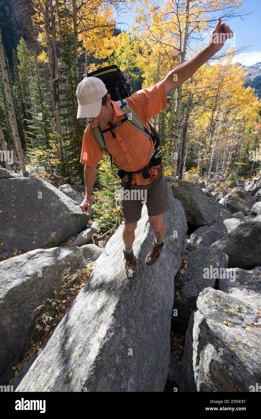 Backpacker balancing as he walks along the narrow top edge of a boulder ...