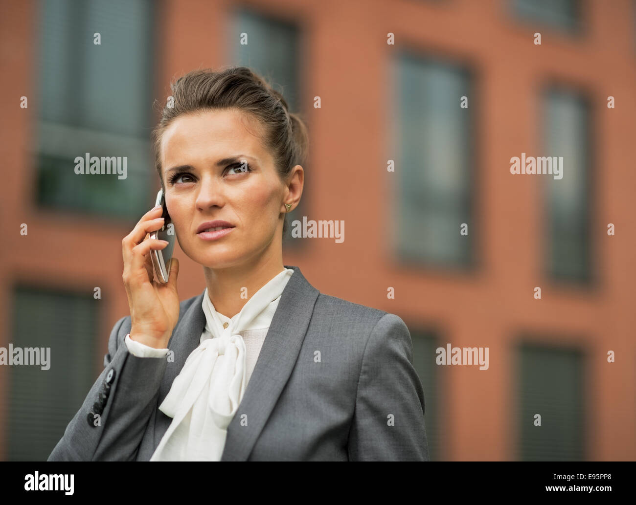 Serious business woman talking cell phone in front of office building ...