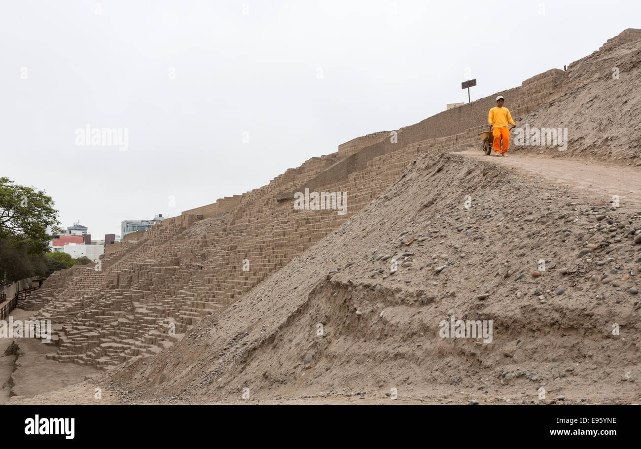Local Peruvian workman working on the adobe pyramid at Huaca Pucllana ...