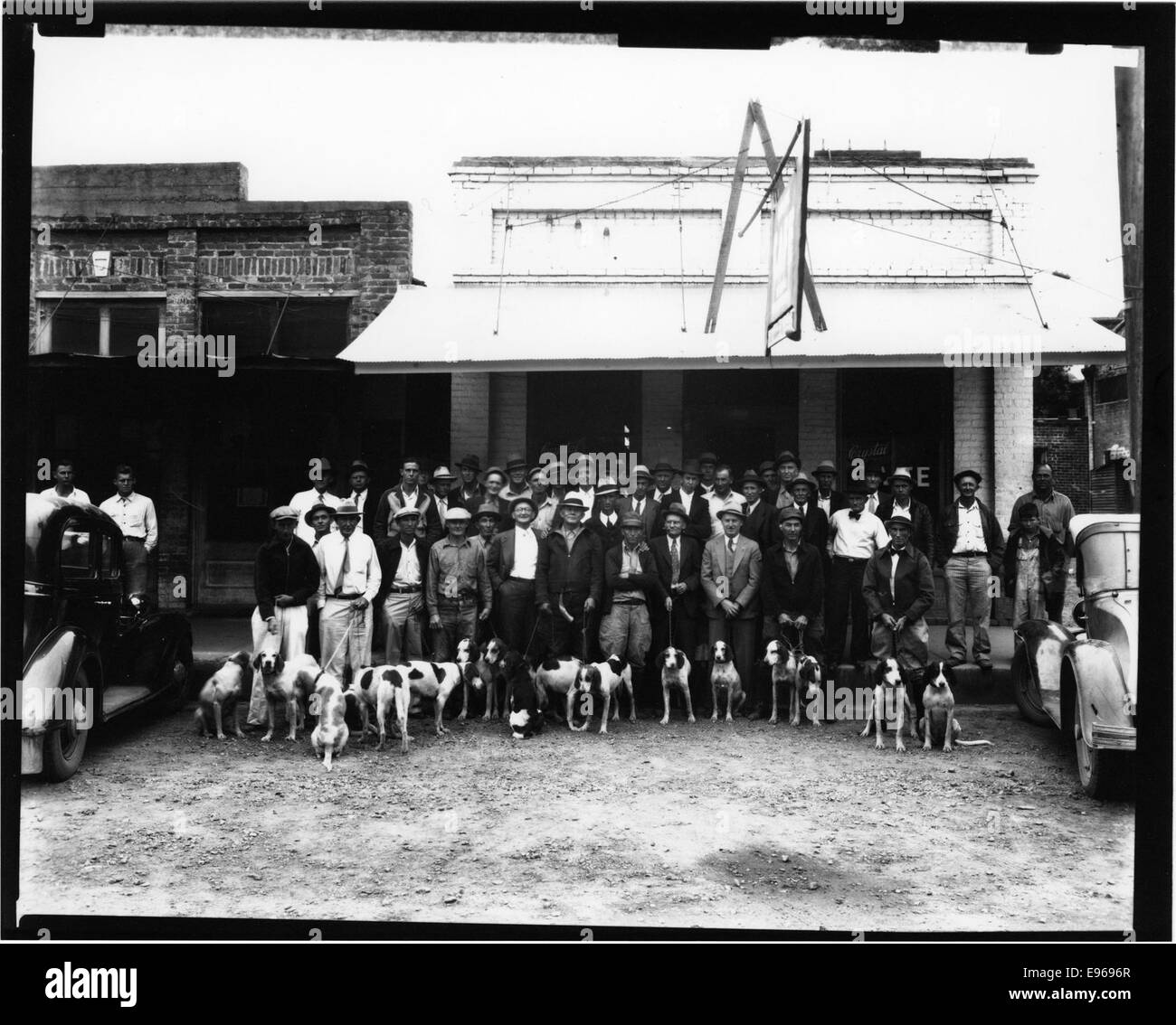 This photograph depicts a group of men standing with their hunting dogs ...