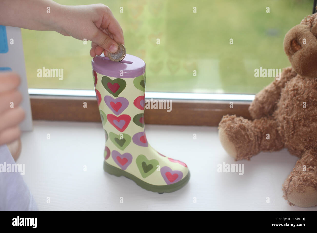 hand putting money in the leg shape coin bank Stock Photo - Alamy
