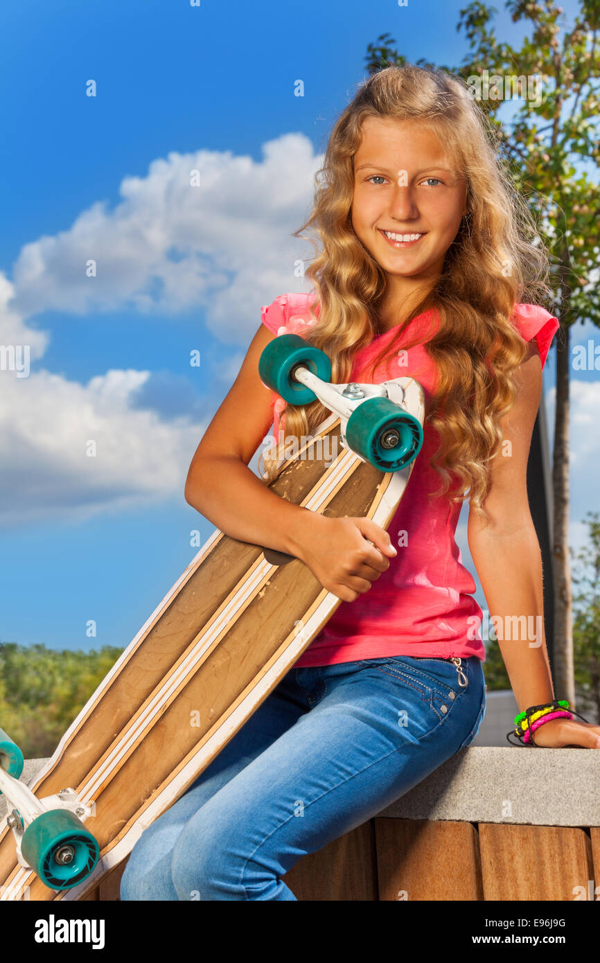 Positive girl holds skateboard sitting in park Stock Photo - Alamy
