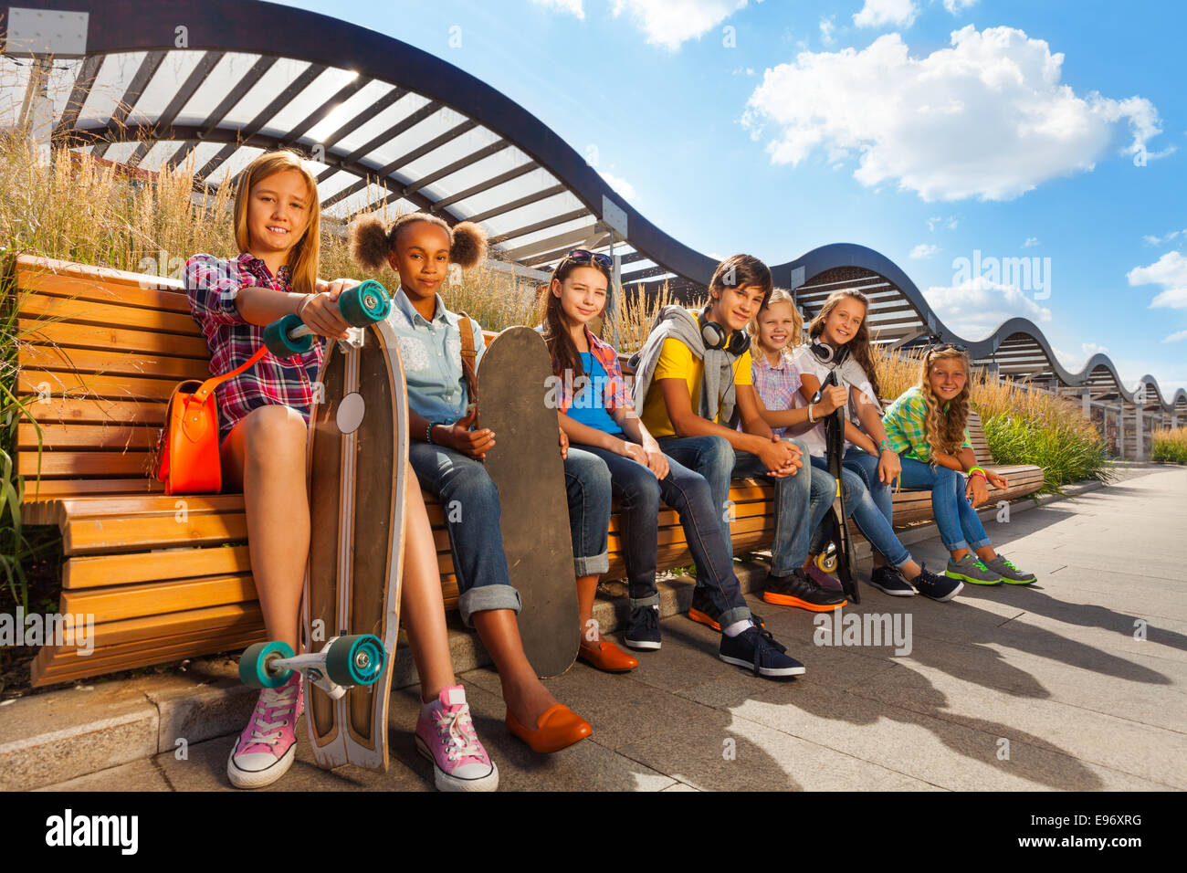 View of happy kids who sit on wooden bench Stock Photo - Alamy