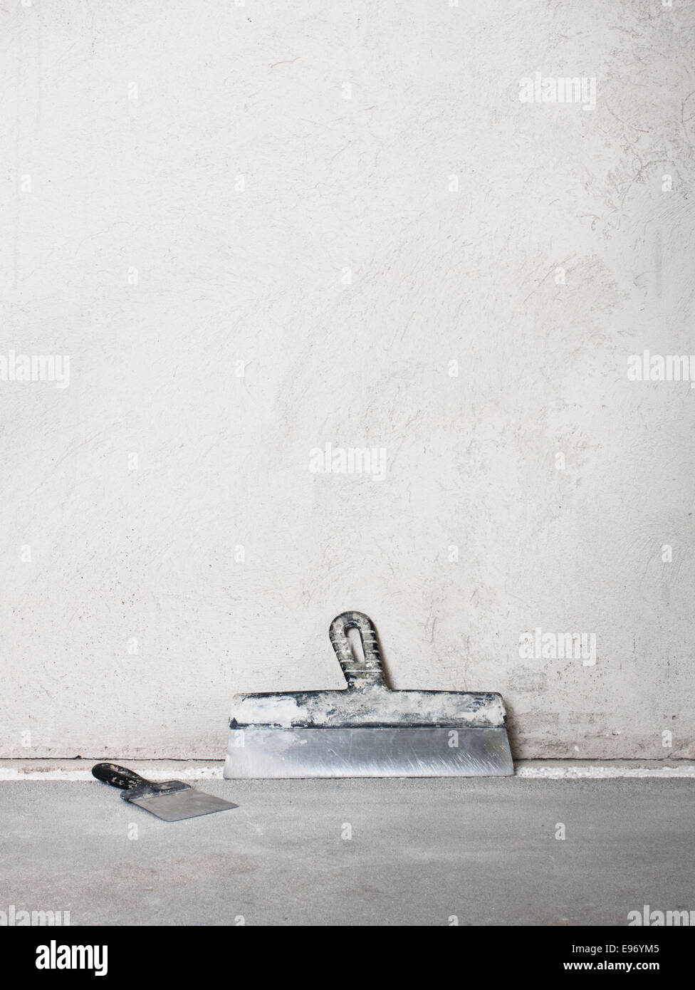 Masonry trowels near a grey plaster wall Stock Photo - Alamy