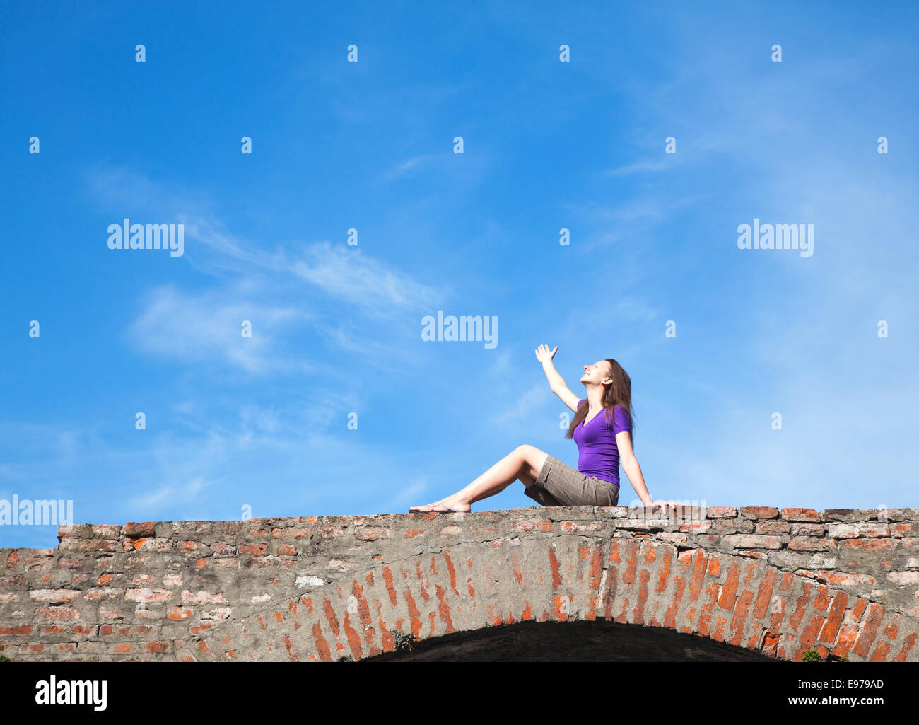 Young woman sitting with raised hand Stock Photo - Alamy