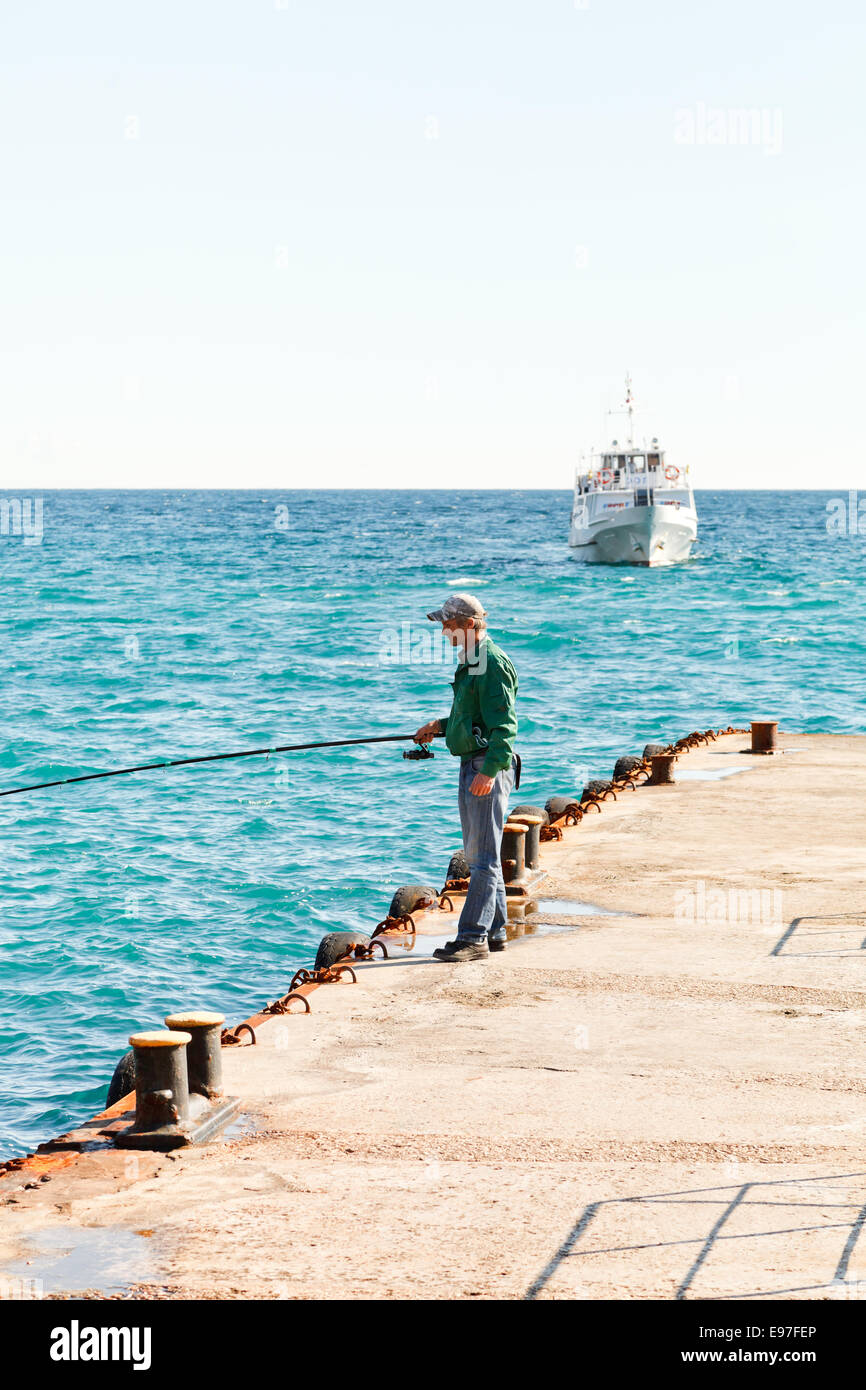 GASPRA, RUSSIA - SEPTEMBER 29, 2014: fisherman fishing by rod from pier ...