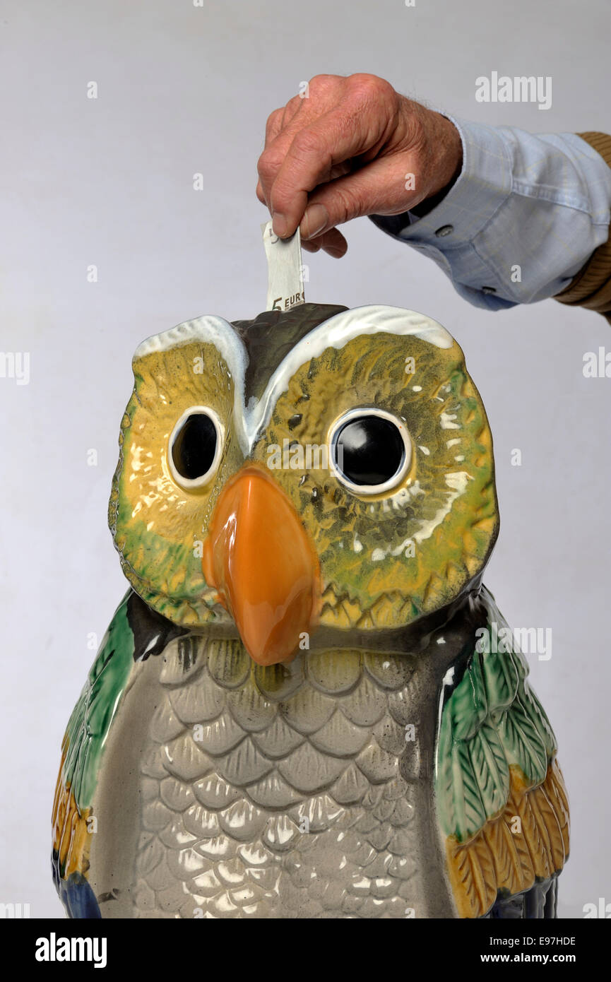 Putting money into owl shaped money box Stock Photo - Alamy