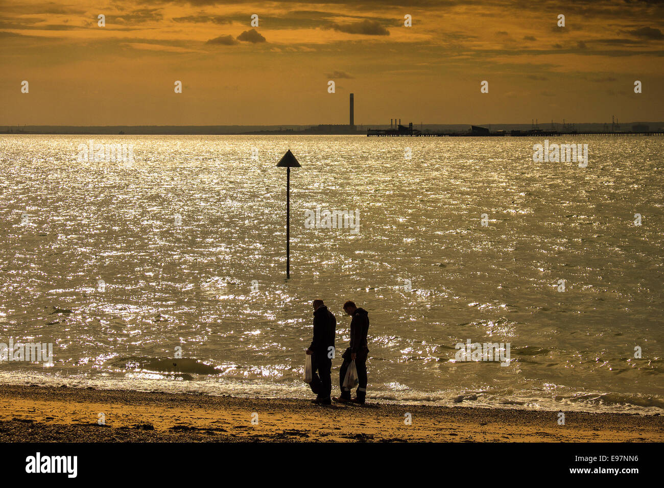 Two people beachcombing along the shoreline at Southend in Essex Stock ...