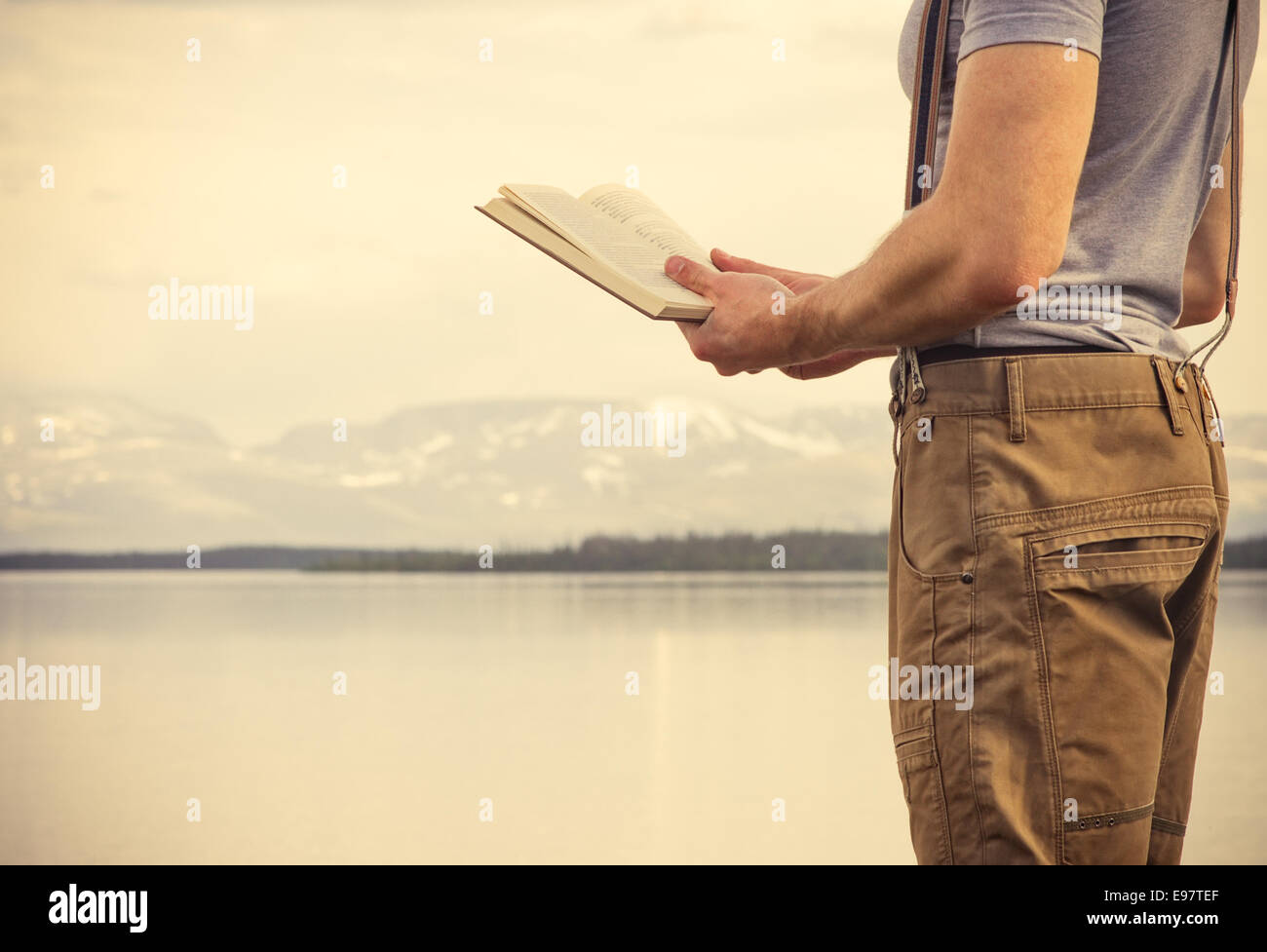 Young Man reading book outdoor with mountains on background Education ...