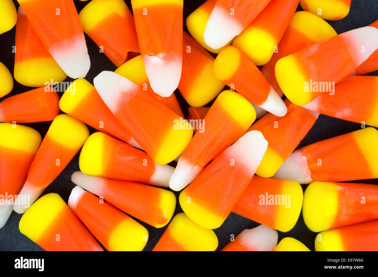 A very close view of Halloween candy corn kernels on a dark background ...